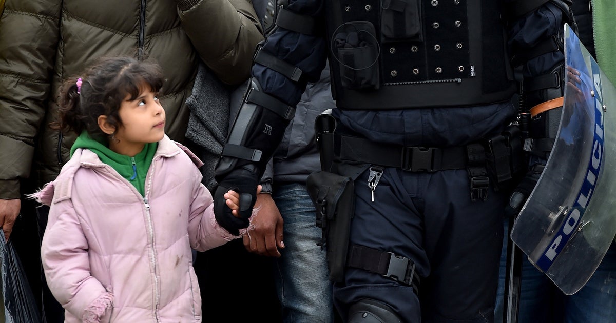 Police Officer And Young Refugee Girl Cross Border Hand In Hand ...